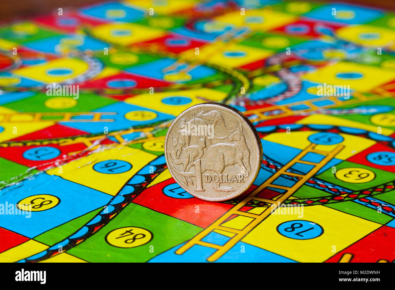 Retro snakes and ladders board with Australian dollar coin in studio ...