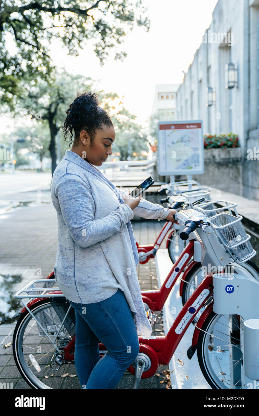 Black woman paying for bicycle rental with cell phone Stock Photo - Alamy