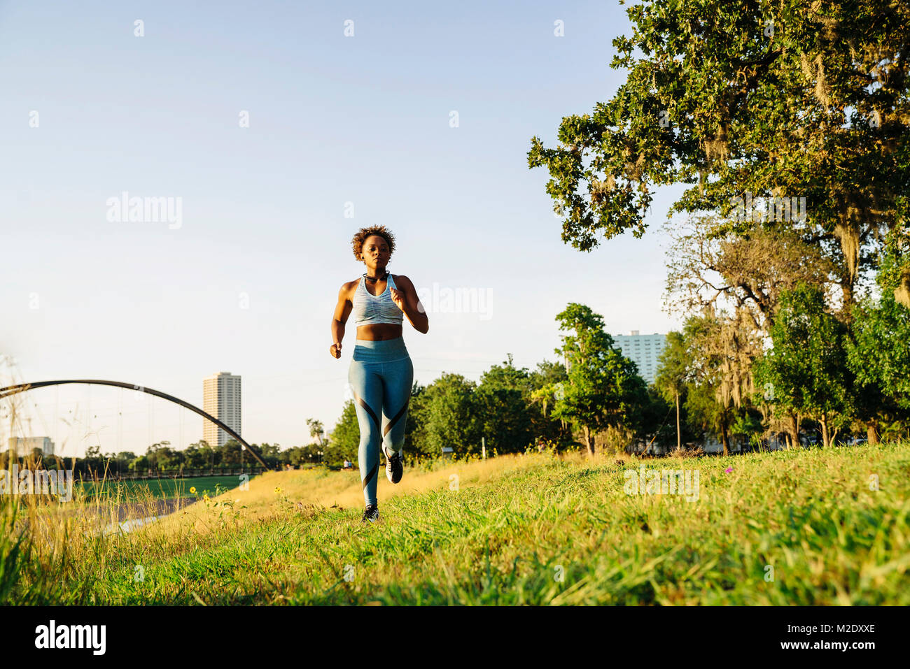 Mixed Race woman running in grass near waterfront Stock Photo - Alamy