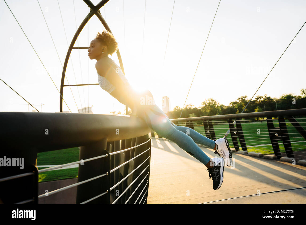 Curious mixed race woman leaning on bridge railing Stock Photo - Alamy