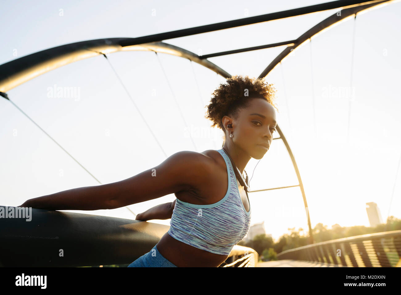 Portrait of mixed race woman stretching arms by pulling on railing ...