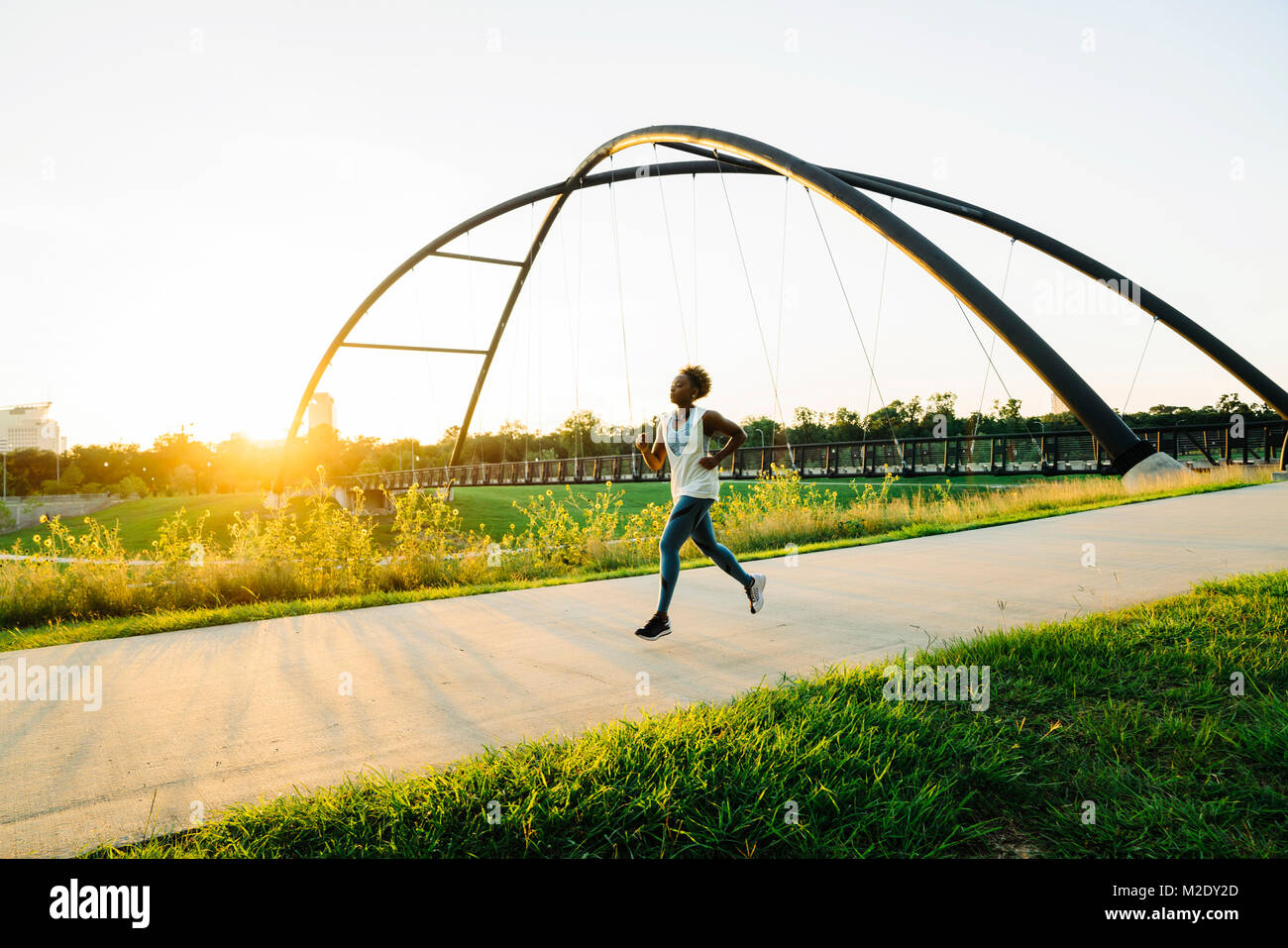 Mixed race woman running on path in park Stock Photo - Alamy