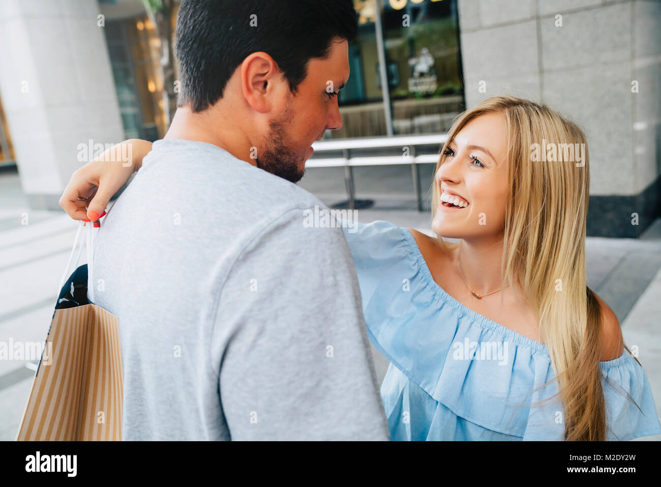 Caucasian couple hugging and carrying shopping bags Stock Photo - Alamy