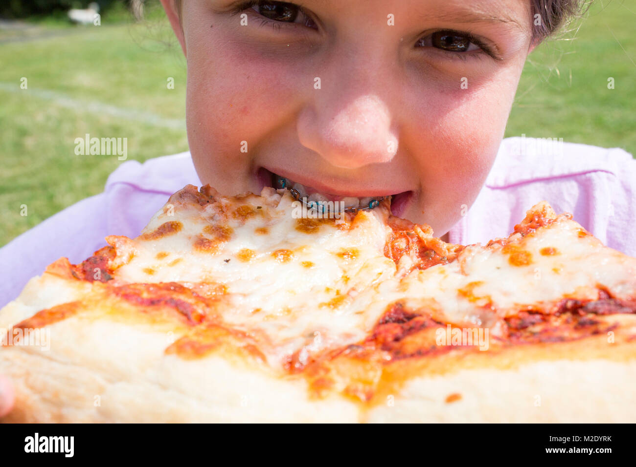 Close up of Caucasian girl with braces biting pizza Stock Photo - Alamy