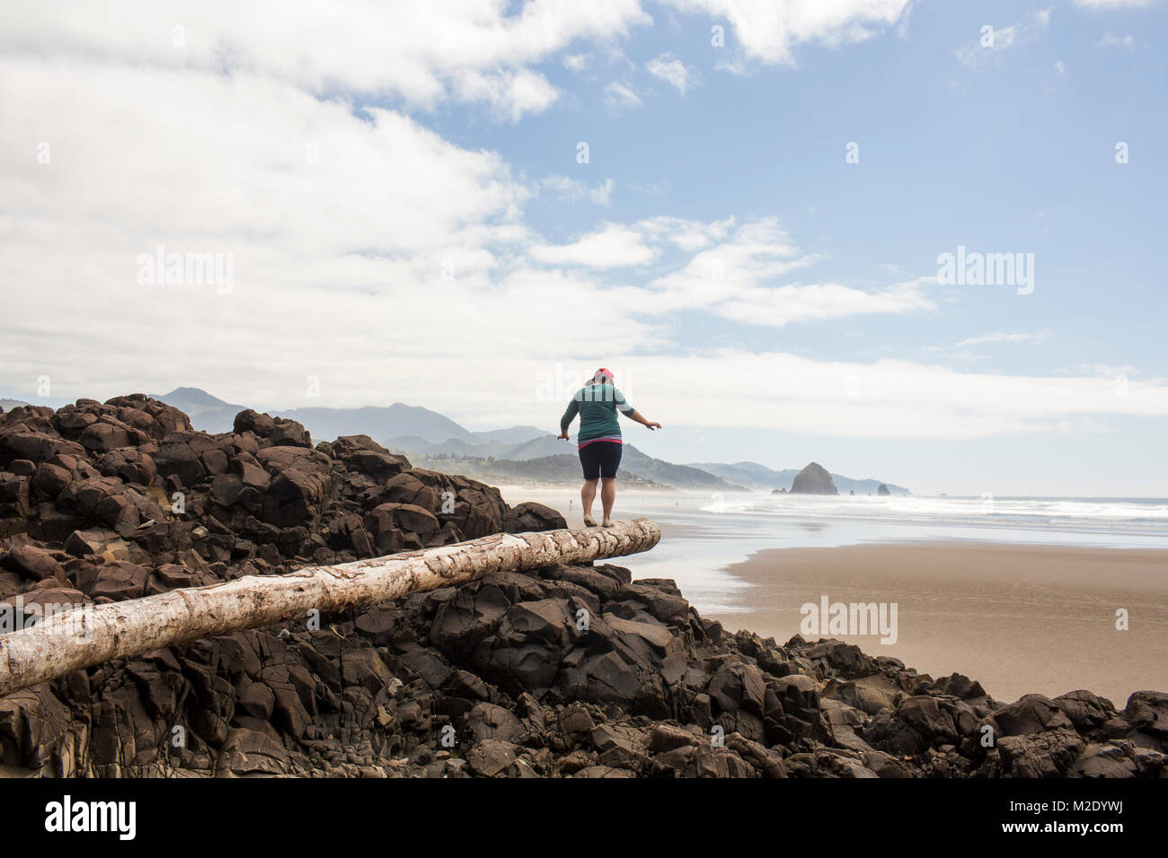 Caucasian woman balancing on log on rocks at beach Stock Photo - Alamy