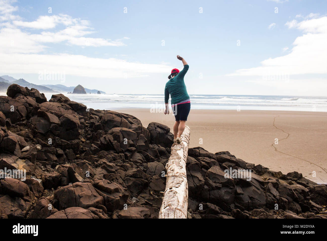 Caucasian woman balancing on log on rocks at beach Stock Photo - Alamy
