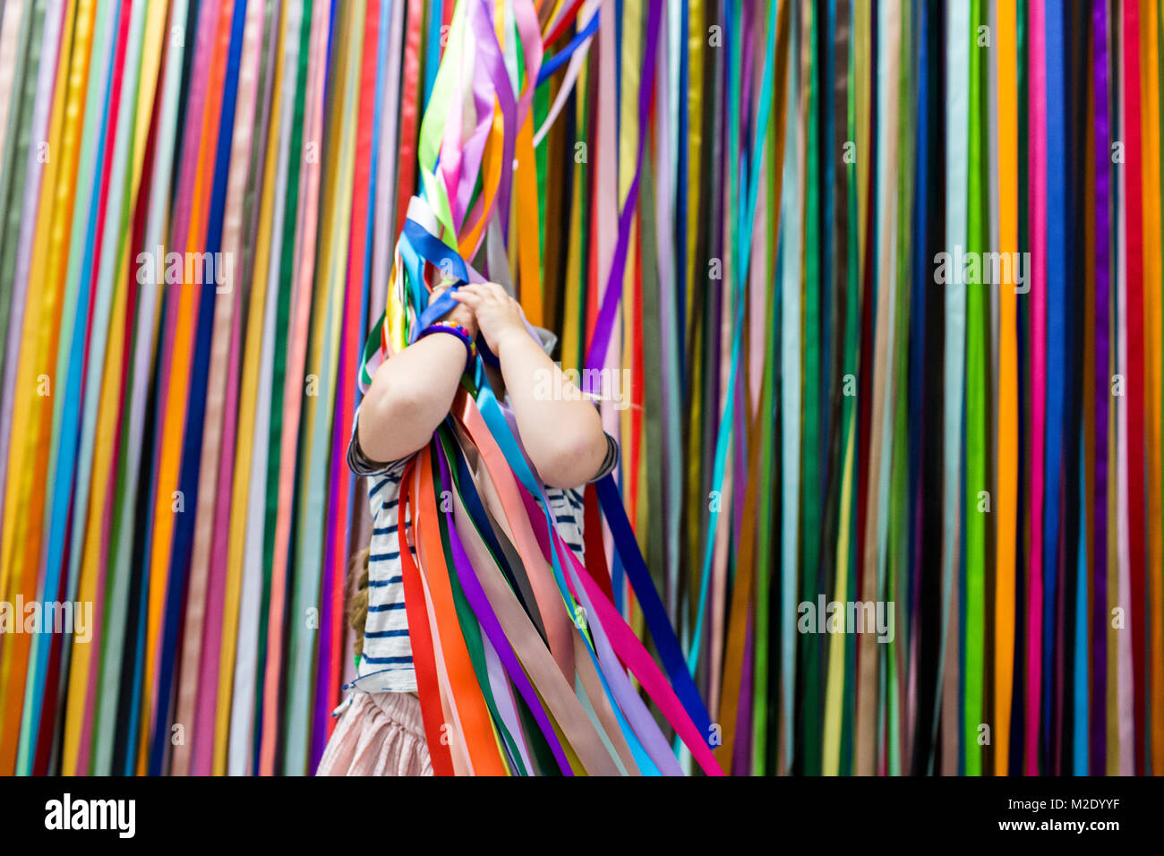 Caucasian girl playing with colorful hanging streamers Stock Photo - Alamy