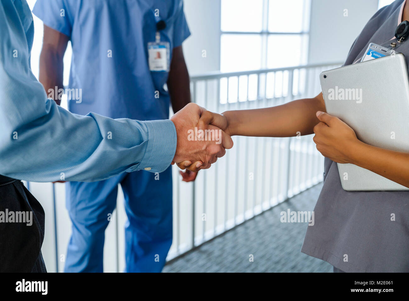Doctor and nurse shaking hands near railing Stock Photo - Alamy