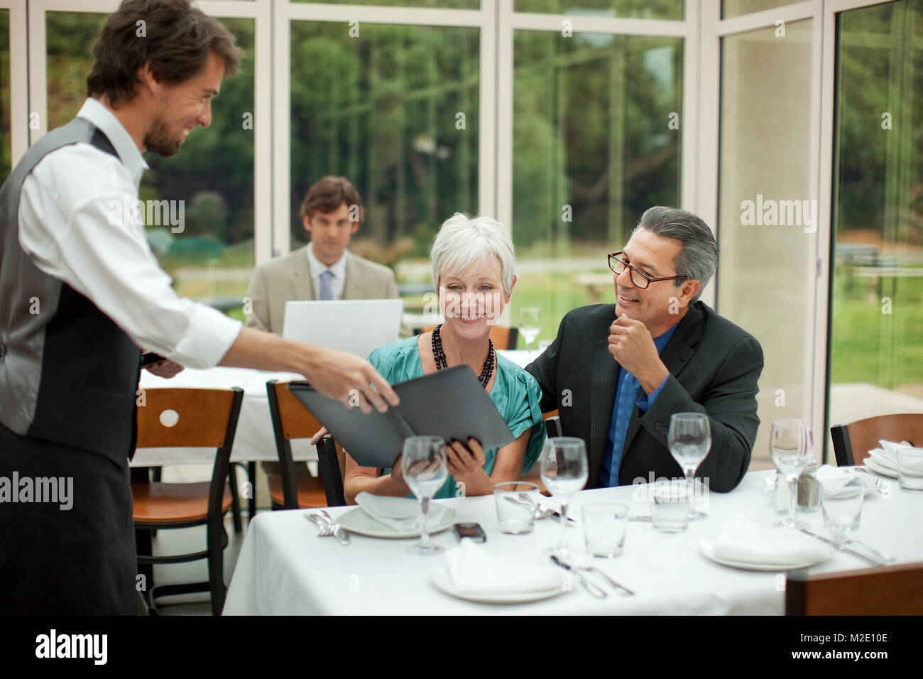 Waiter presenting menu to couple in restaurant Stock Photo - Alamy