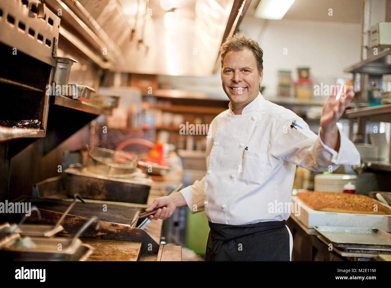 Portrait of Caucasian chef waving in restaurant kitchen Stock Photo - Alamy