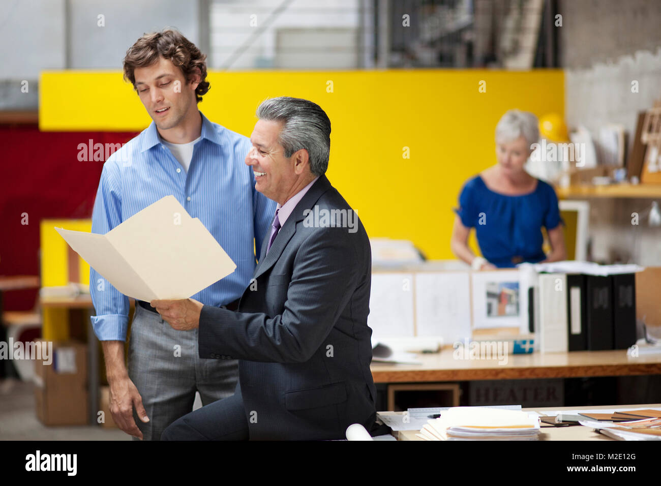 Businessmen reading file folder in office Stock Photo - Alamy