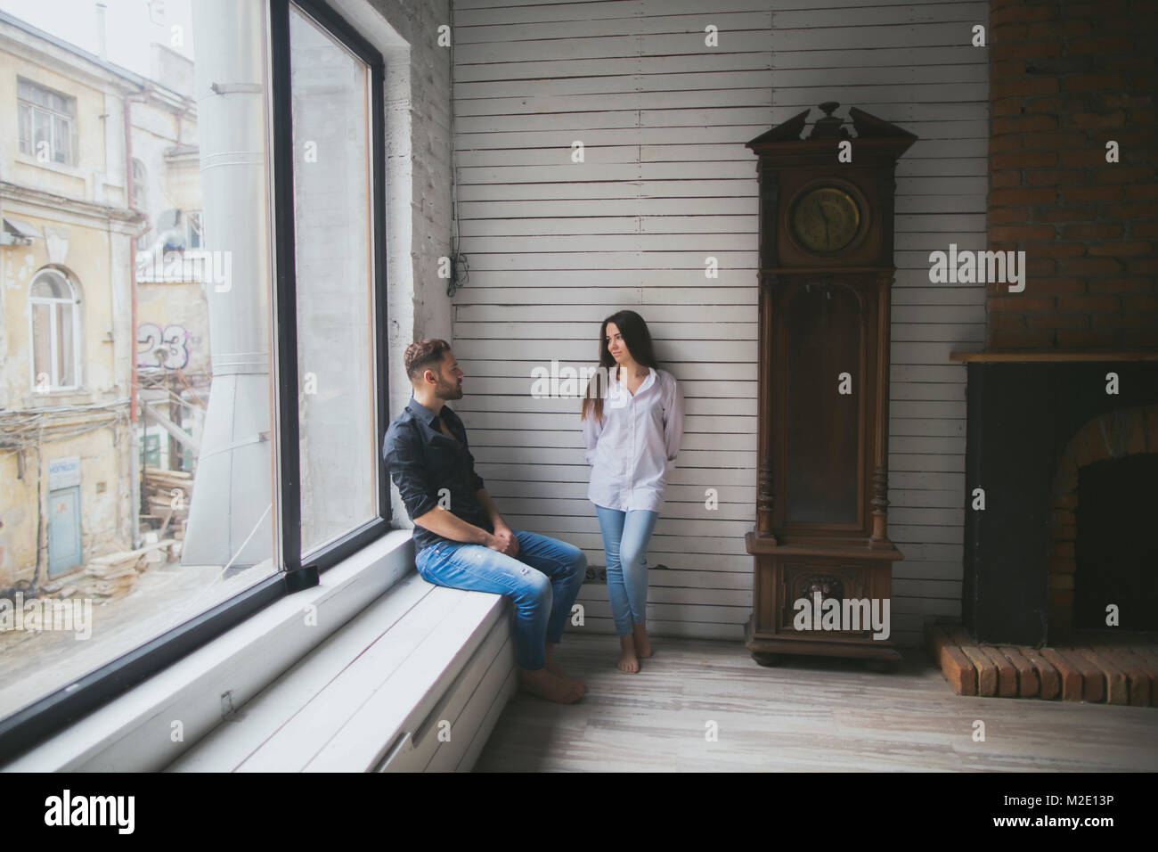 Caucasian couple hanging out near window Stock Photo - Alamy