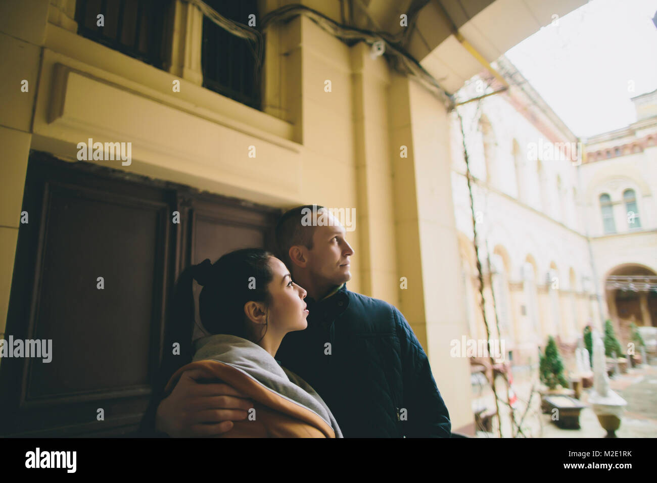 Caucasian couple hugging and leaning on wall in courtyard Stock Photo ...