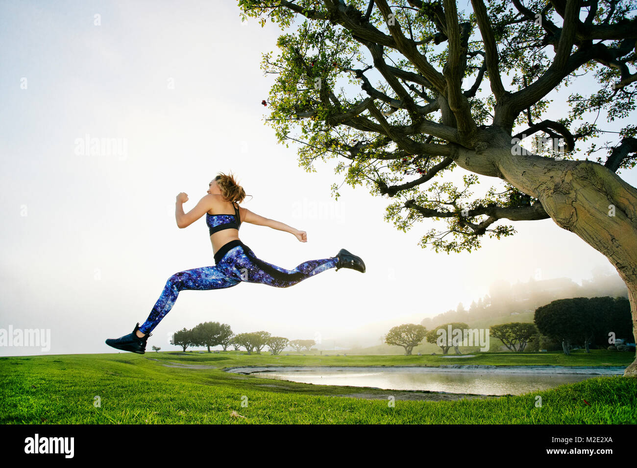 Mixed race woman running near lake Stock Photo - Alamy