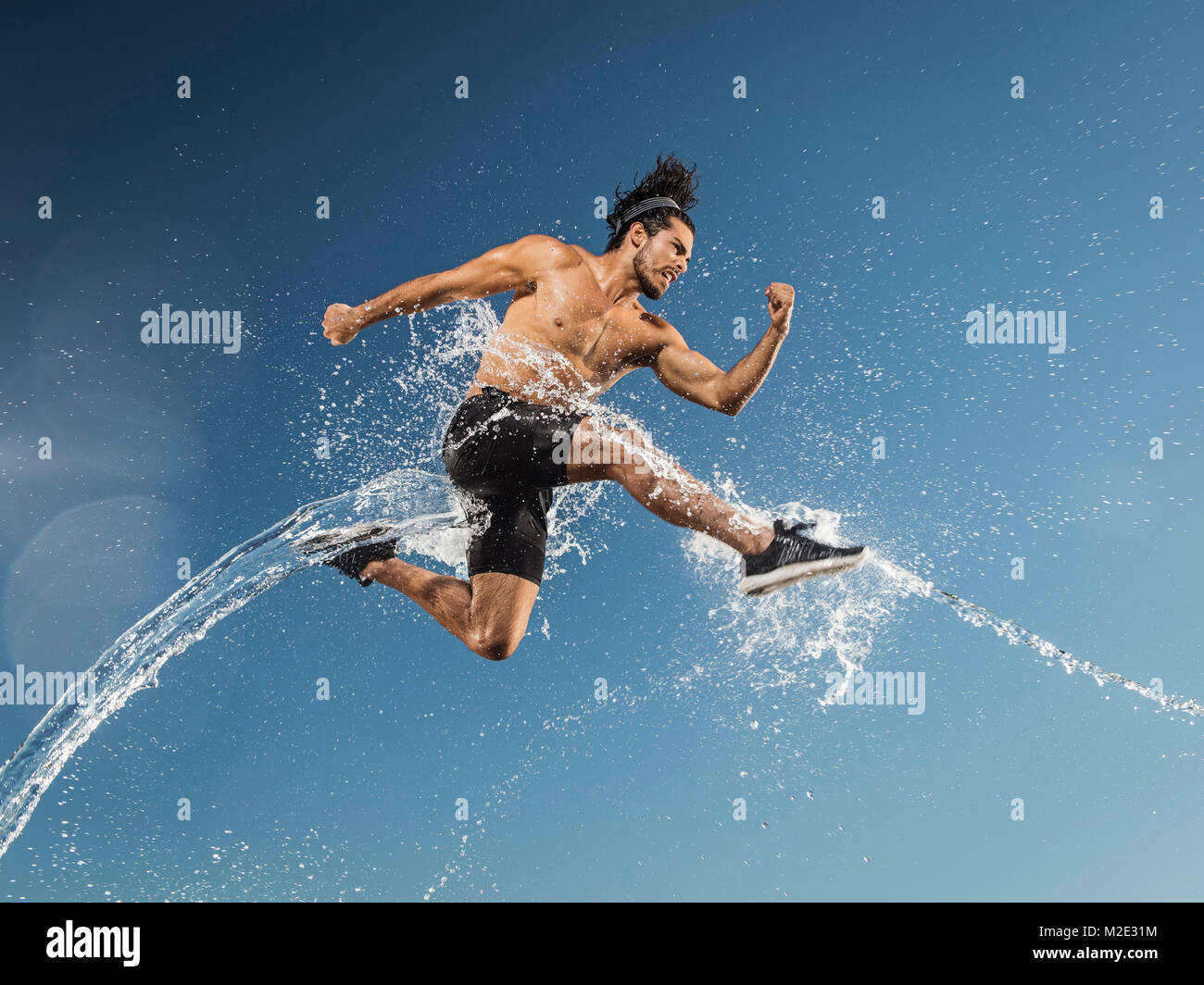 Water splashing on Hispanic man running and jumping Stock Photo - Alamy