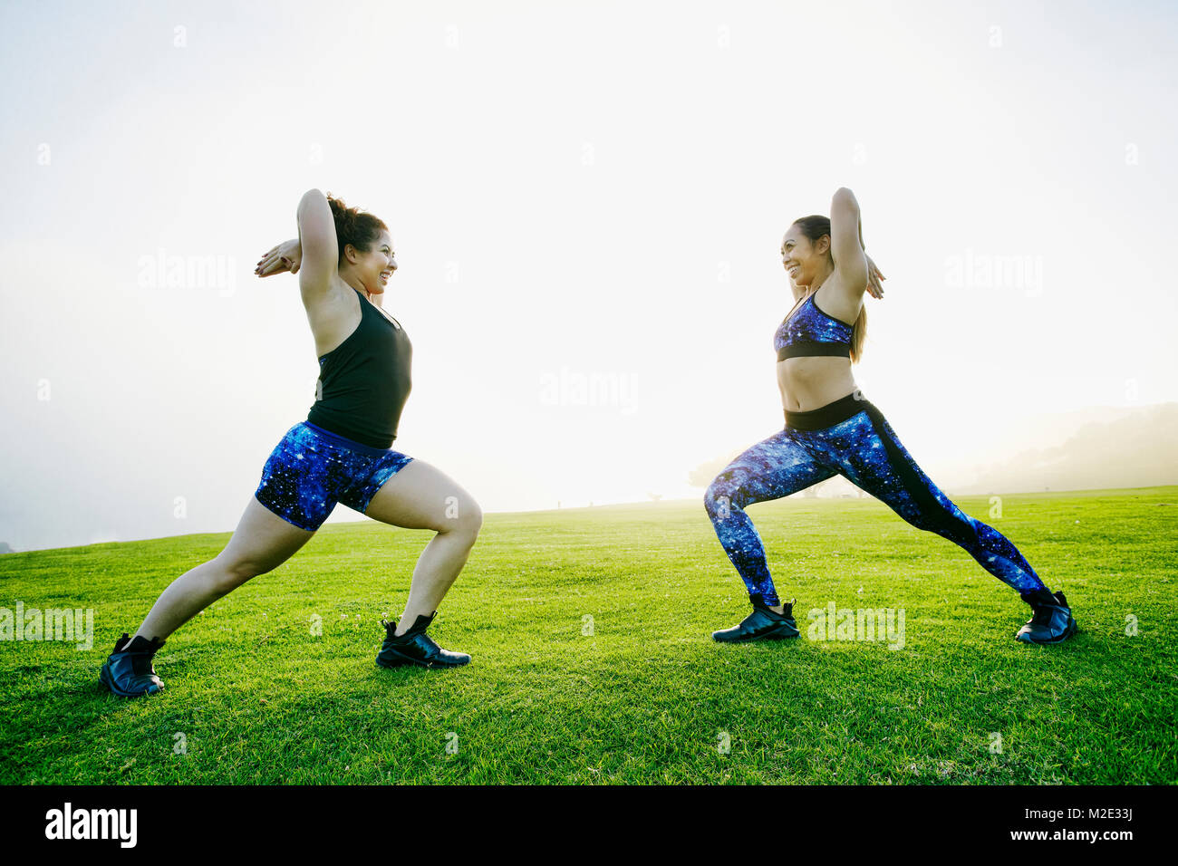 Mixed race women stretching arms in field Stock Photo - Alamy