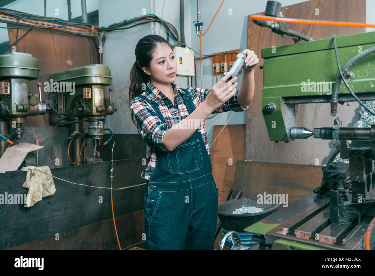 confident young female factory manager looking at processing parts to ...