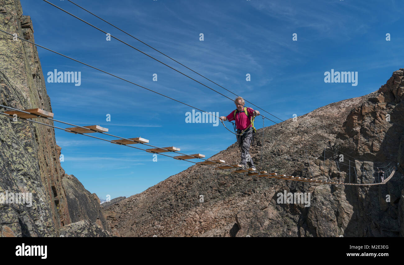 Caucasian man crossing rope bridge on mountain Stock Photo - Alamy