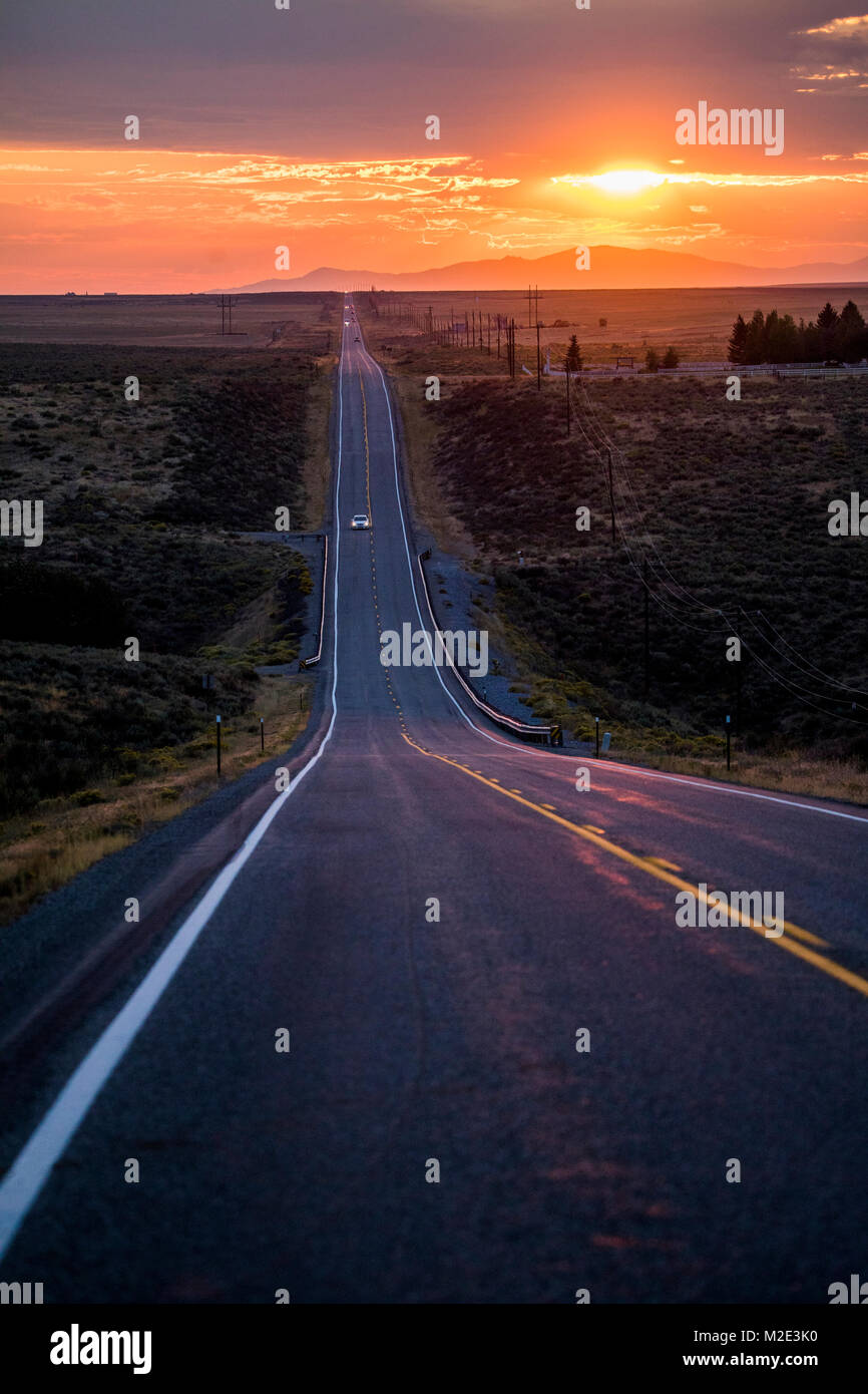 Cars driving on remote road at sunset Stock Photo - Alamy