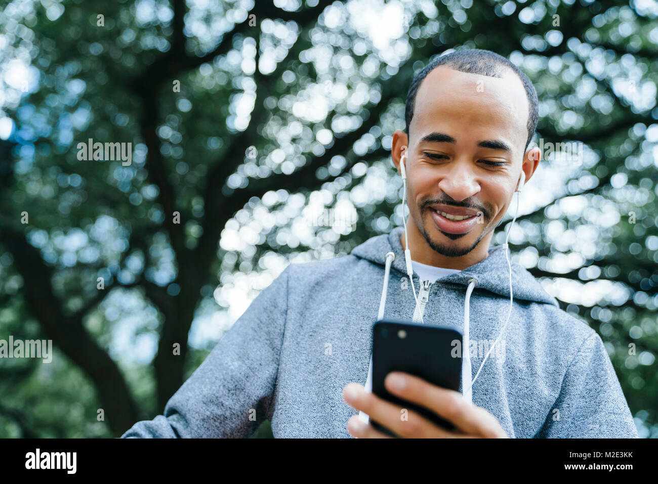 Black man listening to cell phone with earbuds Stock Photo - Alamy