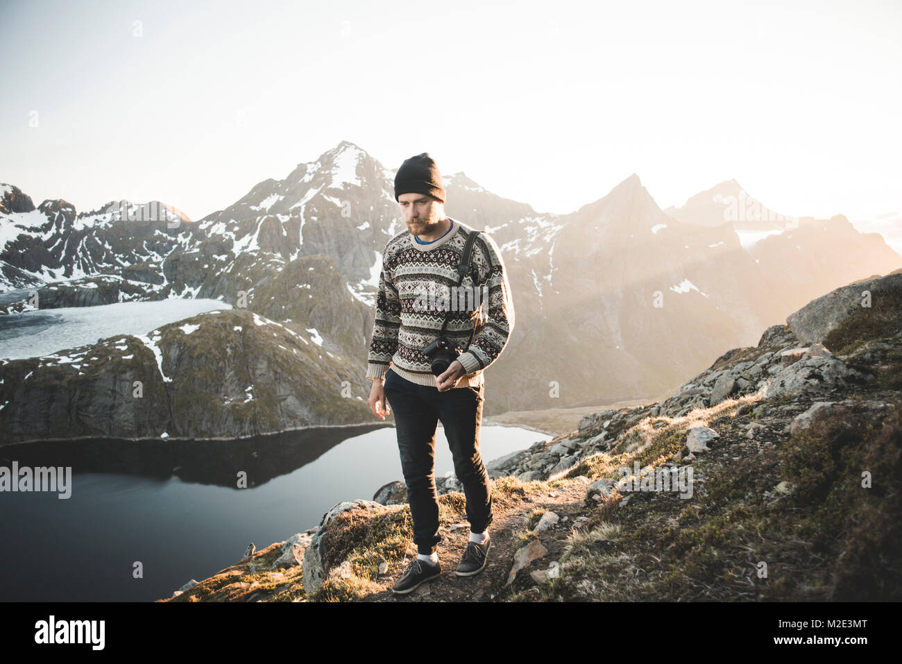 Caucasian man carrying camera near mountain lake Stock Photo - Alamy
