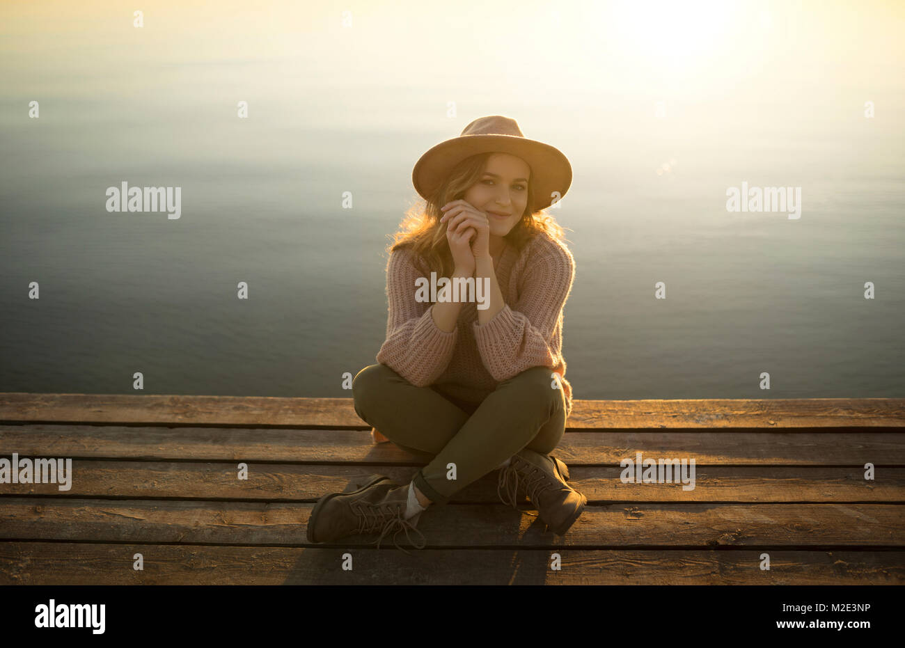 Smiling Caucasian woman sitting on dock of lake Stock Photo - Alamy