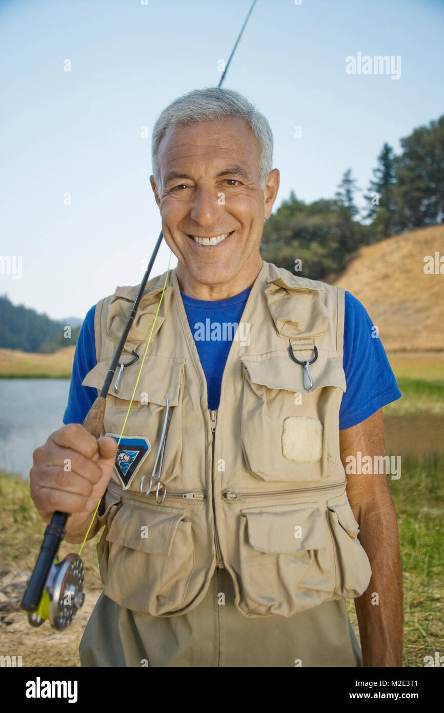 Portrait of smiling Caucasian man holding fishing rod Stock Photo - Alamy