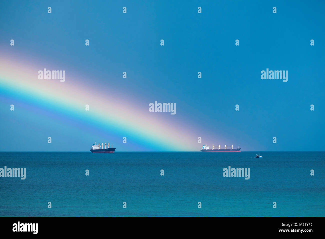 A rainbow at sea and two container ships at anchor Stock Photo - Alamy