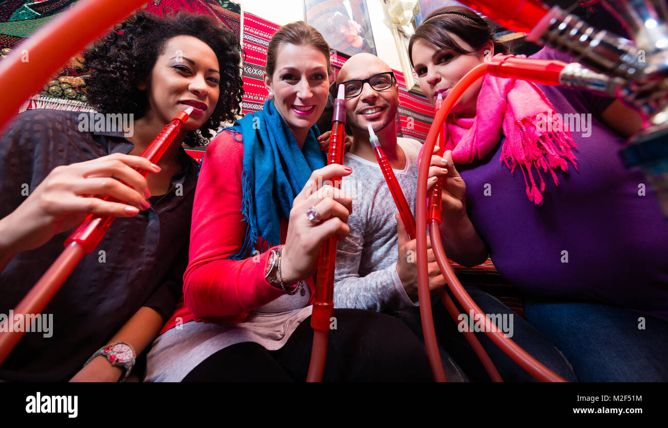 Friends smoking a hookah in shisha lounge Stock Photo - Alamy