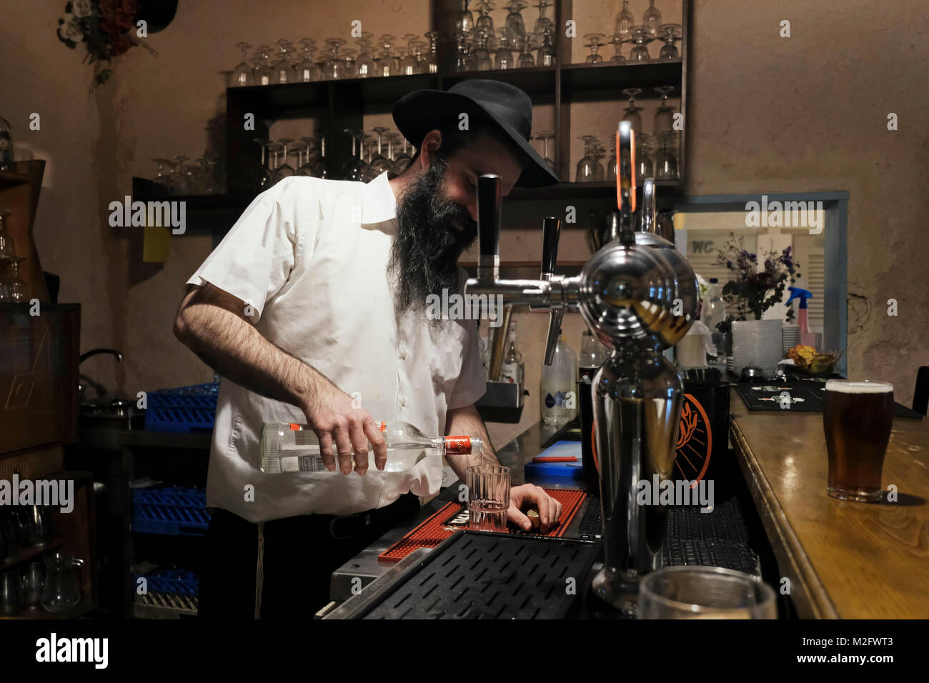 An orthodox Jewish man pouring alcoholic beverage in a bar in Tel Aviv ...