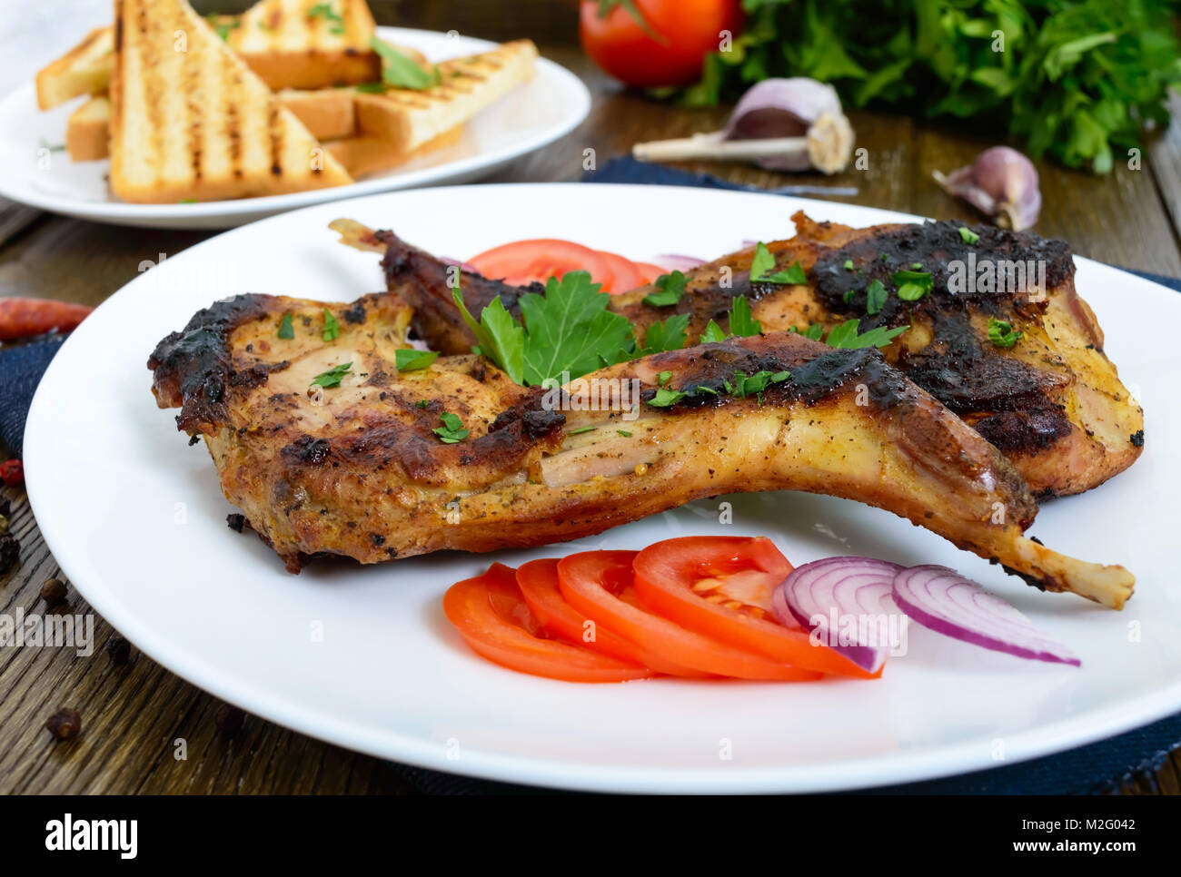 Fried rabbit legs on a white plate on a wooden table. Dietary rabbit ...