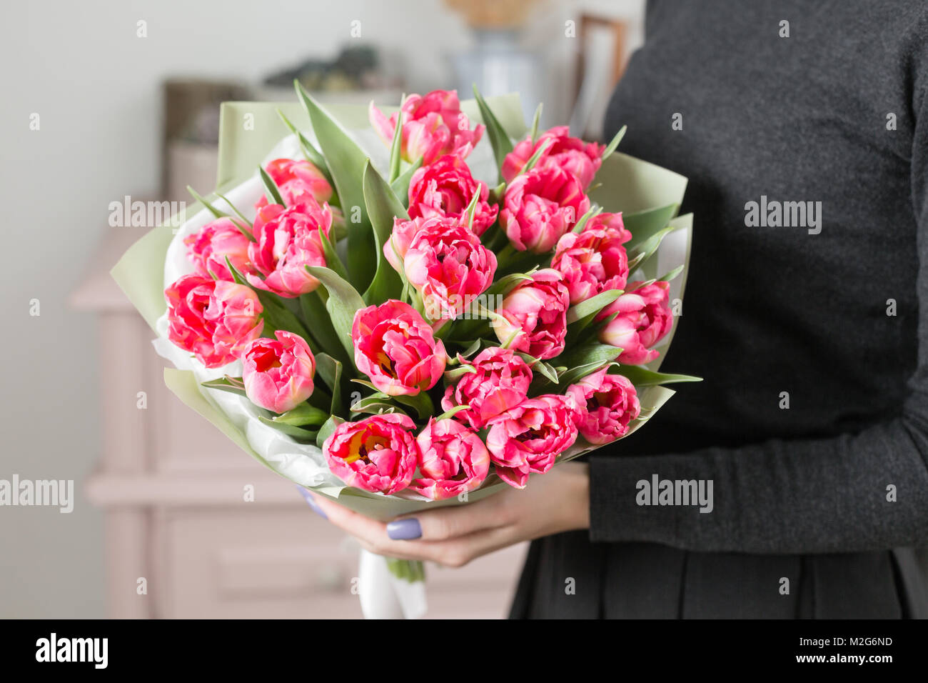 beautiful luxury bouquet of pink tulips flowers in woman hand. the work of the florist at a ...