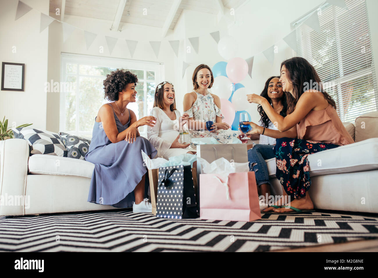 Group of diverse women sitting together at baby shower of female friend ...