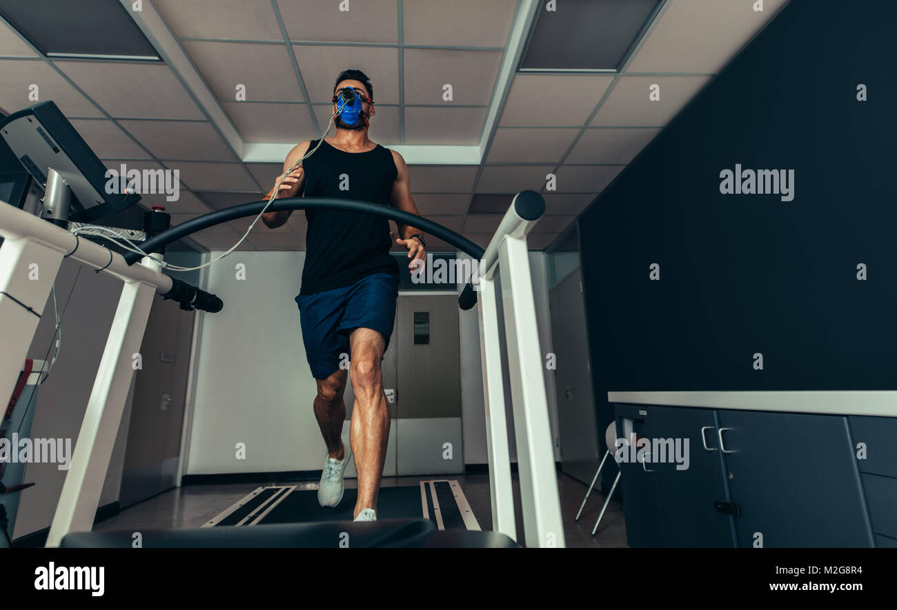 Male athlete with mask running on treadmill to analyze his fitness ...
