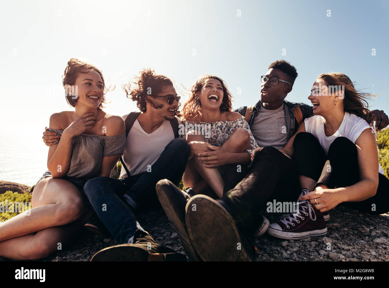 Group of friends sitting together on mountain top and enjoying ...
