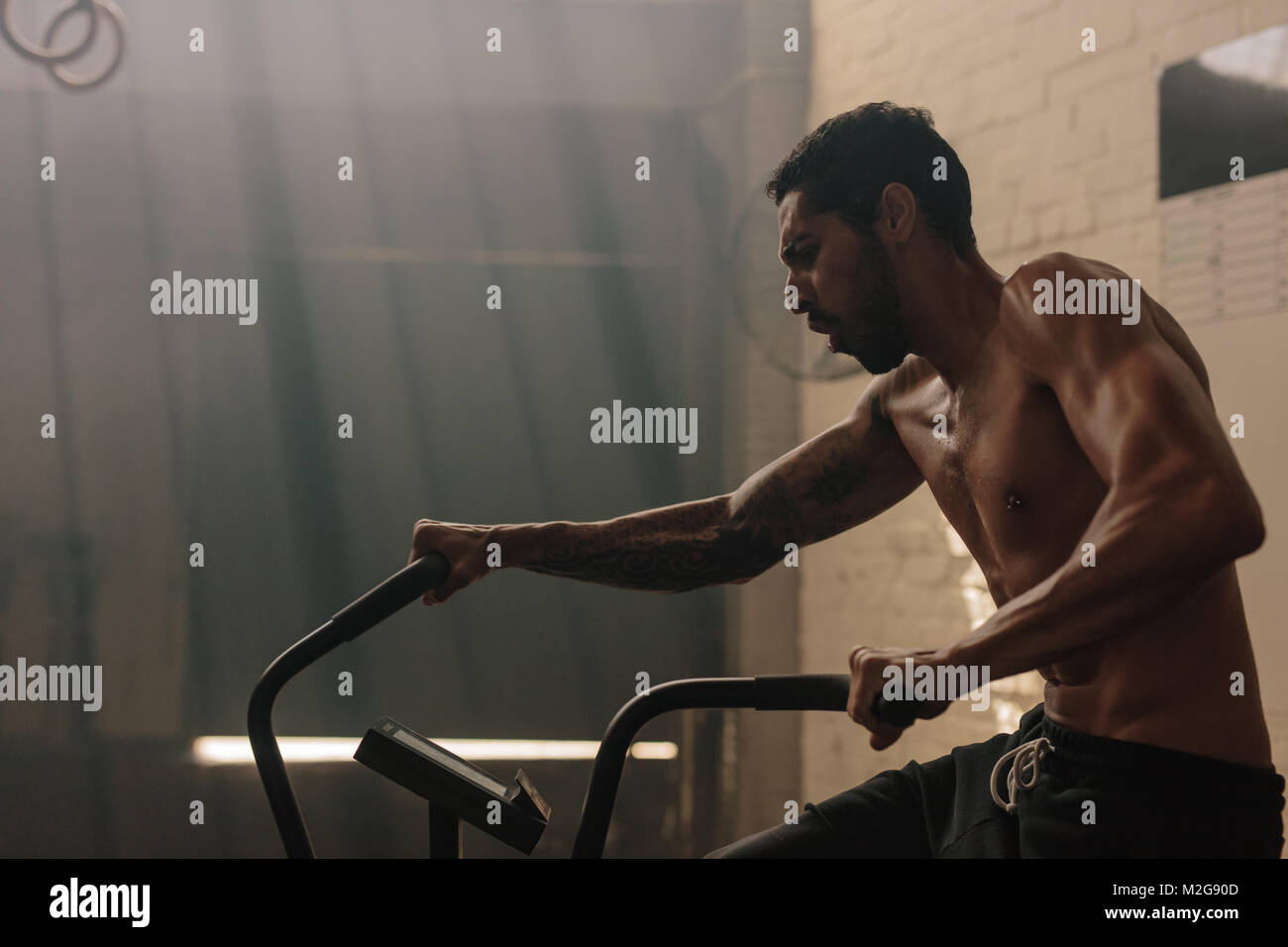 Fit young man using exercise bike at the gym. Fitness male using air ...