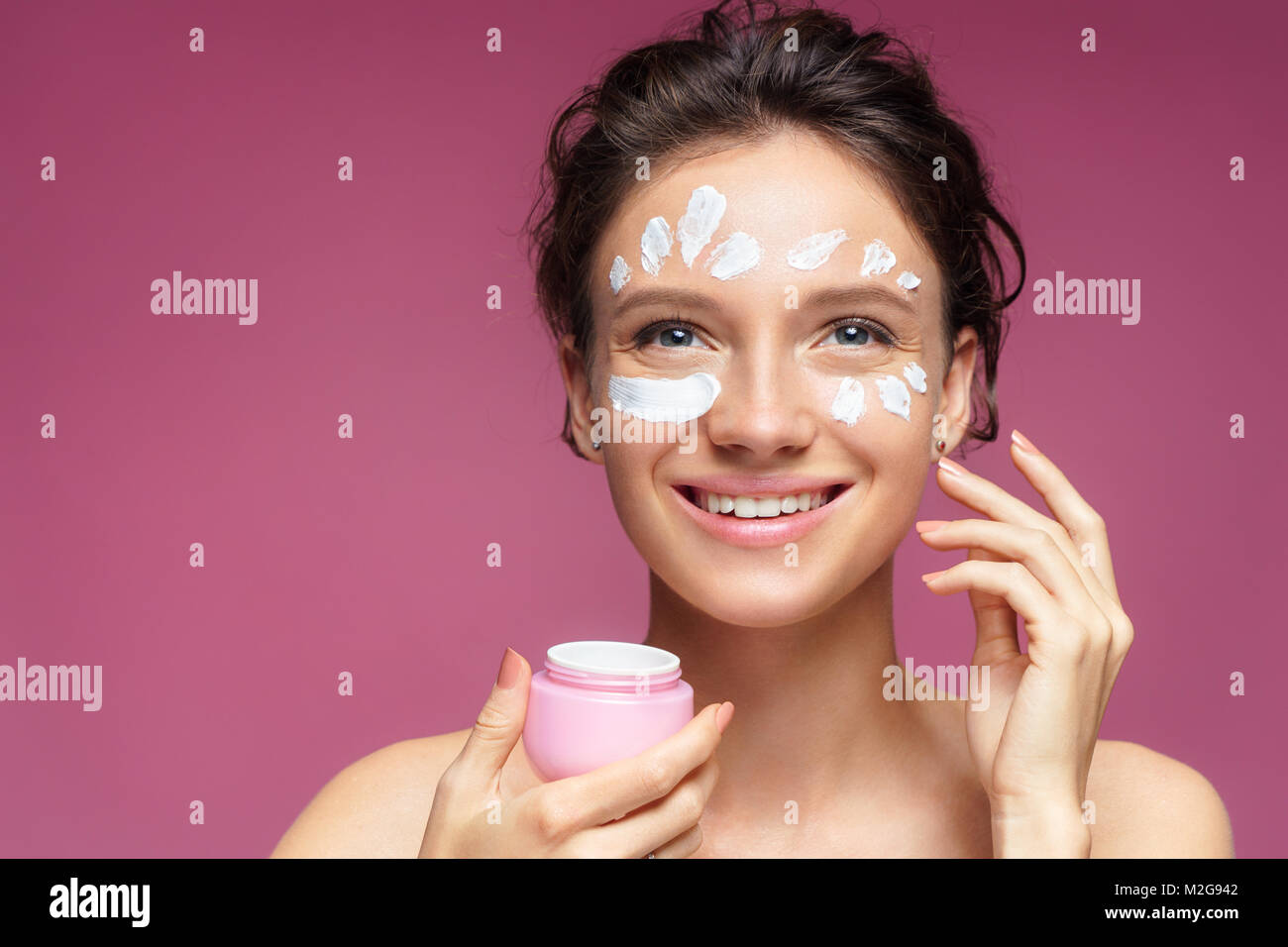 Woman applying cream. Photo of smiling woman with healthy skin on pink ...