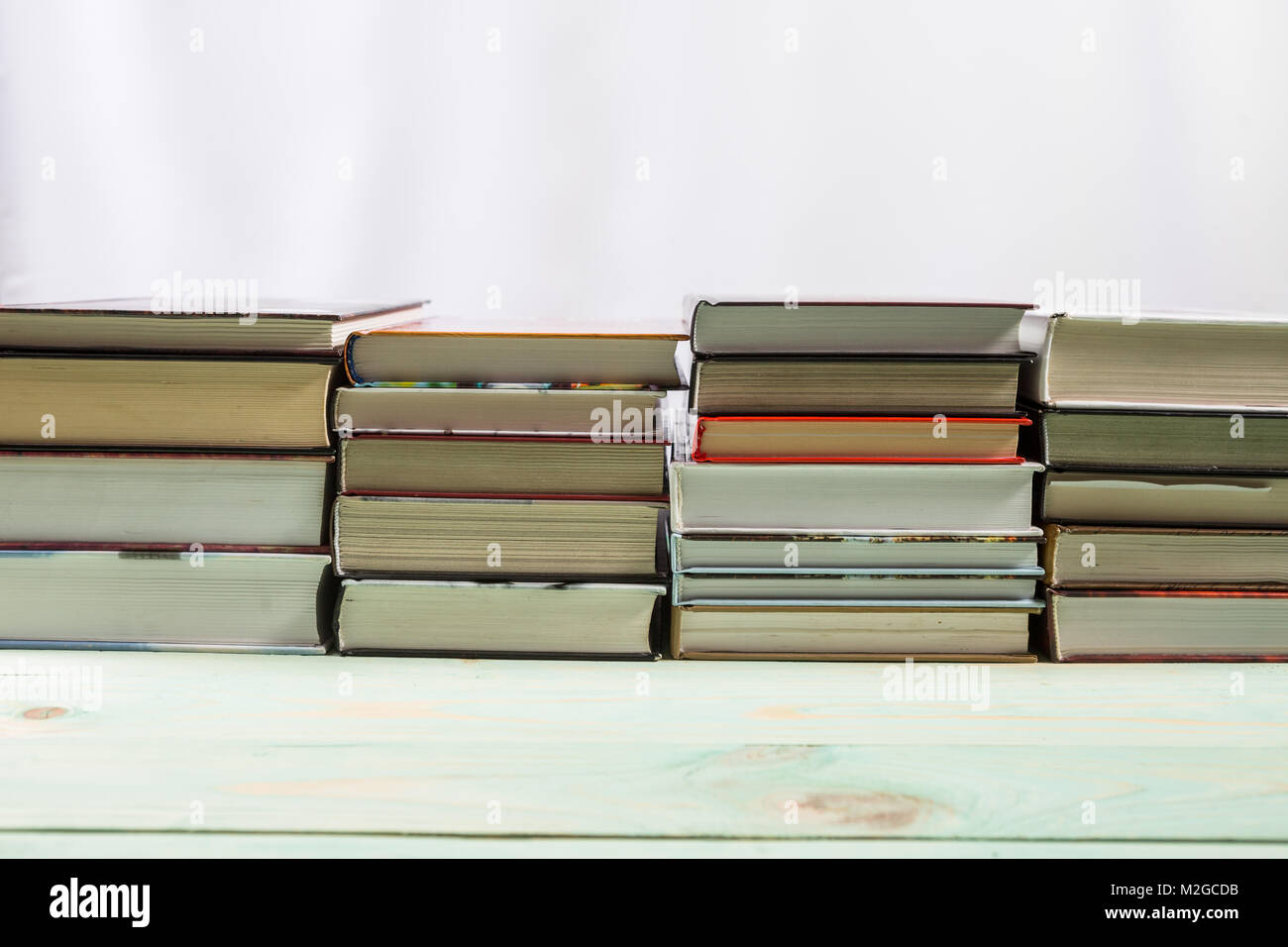 Pile of various books on bright wooden background. With copy space for ...