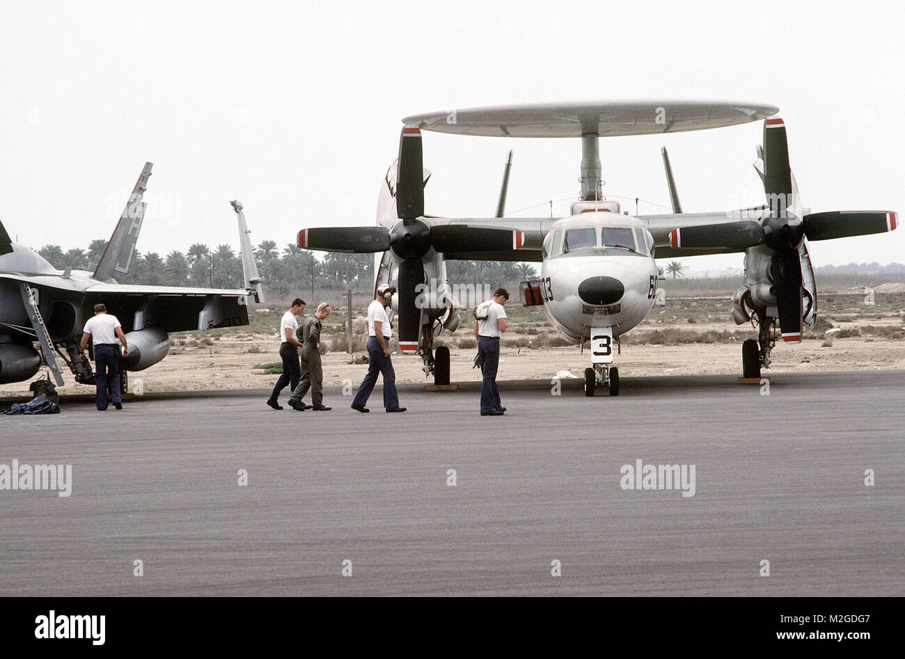 Sailors walk past an E-2C Hawkeye airborne early warning and control ...