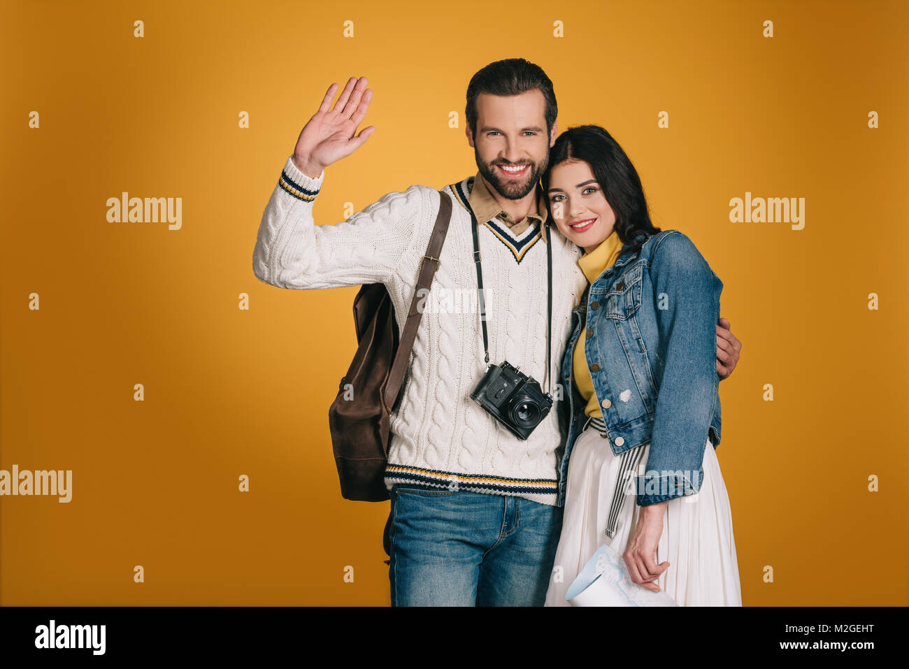 boyfriend waving hand and hugging girlfriend isolated on yellow Stock ...