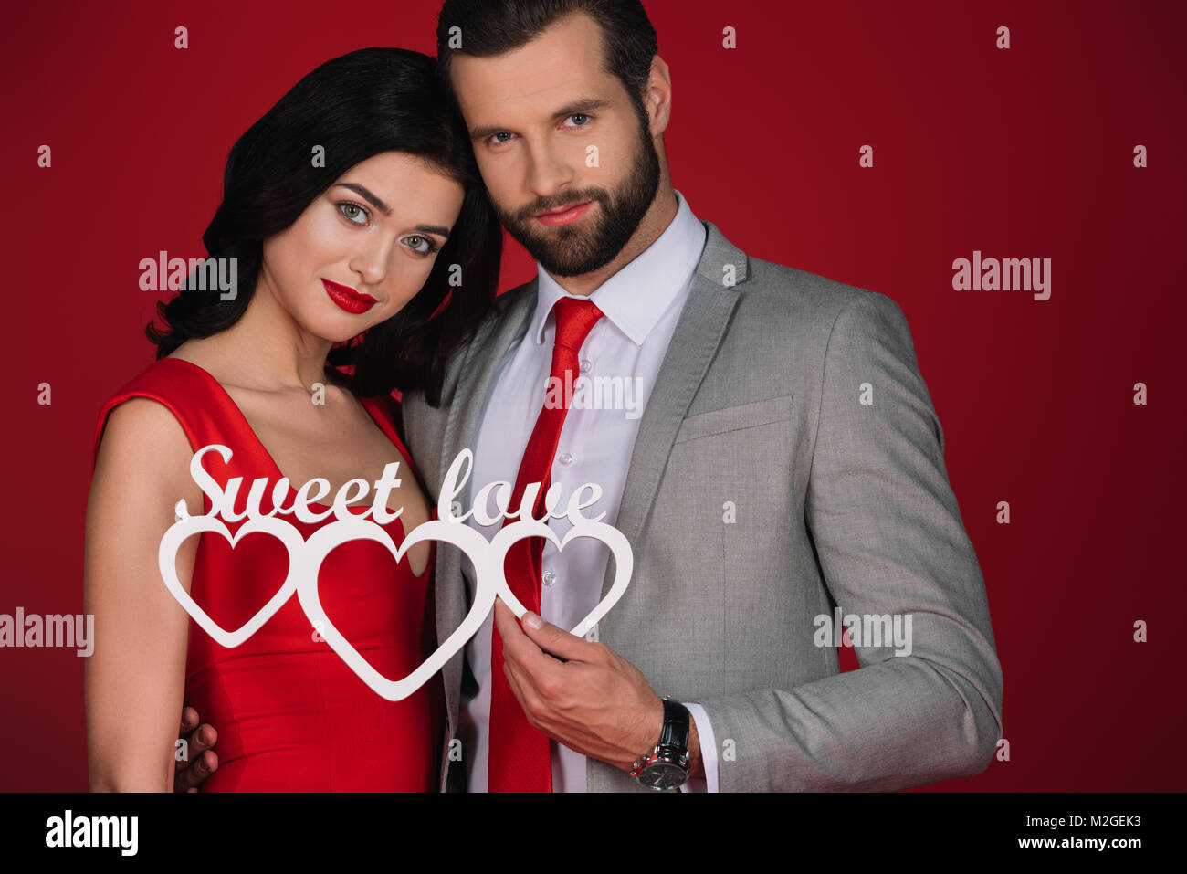 attractive couple holding sign sweet love isolated on red Stock Photo ...