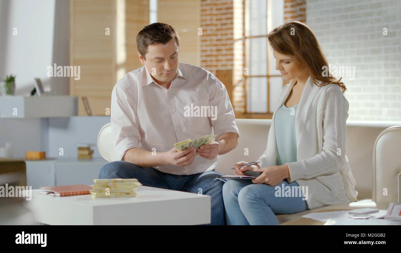 Successful married couple counting cash at home, family budget money ...