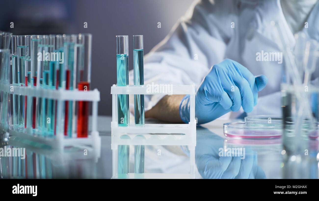 Medical scientist conducting test, observing reactions in glass flasks ...