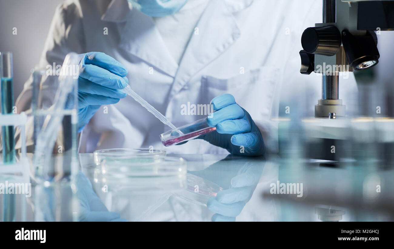 Lab technician checking material by creating chemical reaction with ...