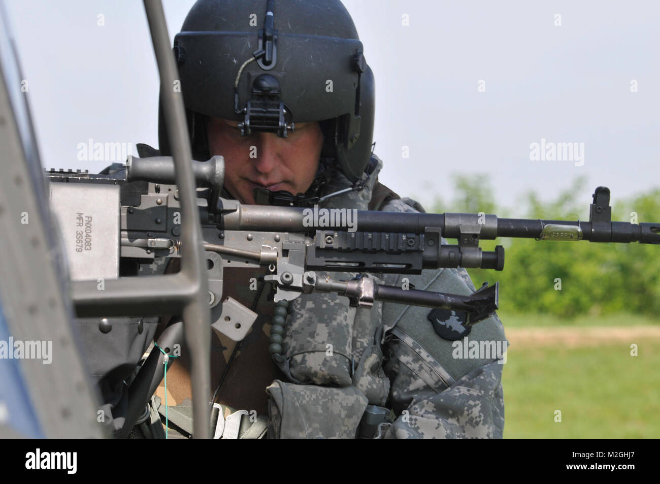 Soldier attaches machine gun to helicopter by EUCOM Stock Photo - Alamy