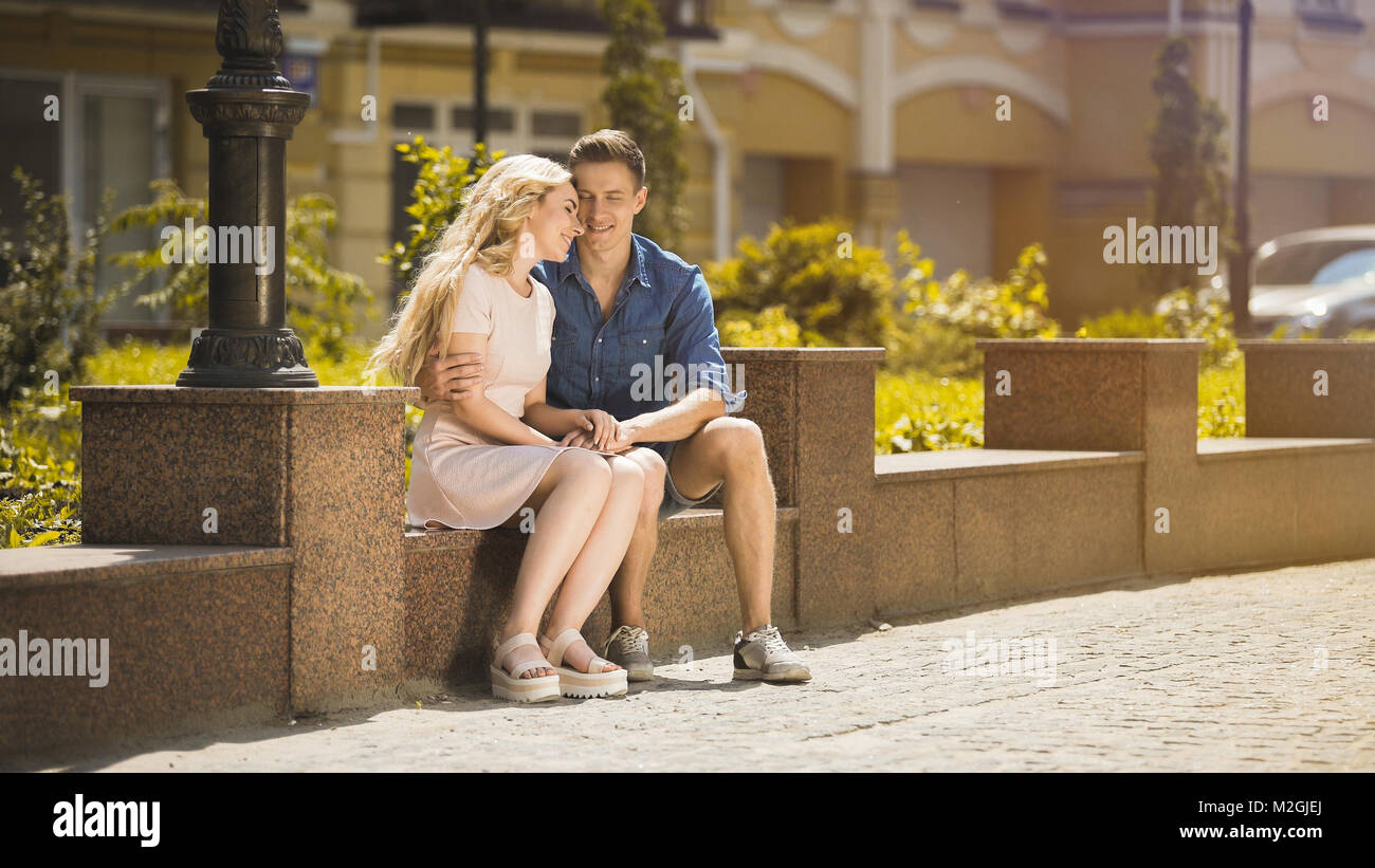 Sweet couple hugging on bench and holding hands, romantic relationship ...