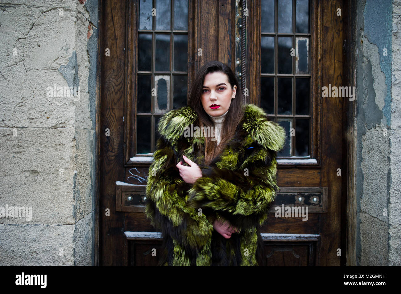 Brunette girl in green fur coat against old wooden doors Stock Photo ...
