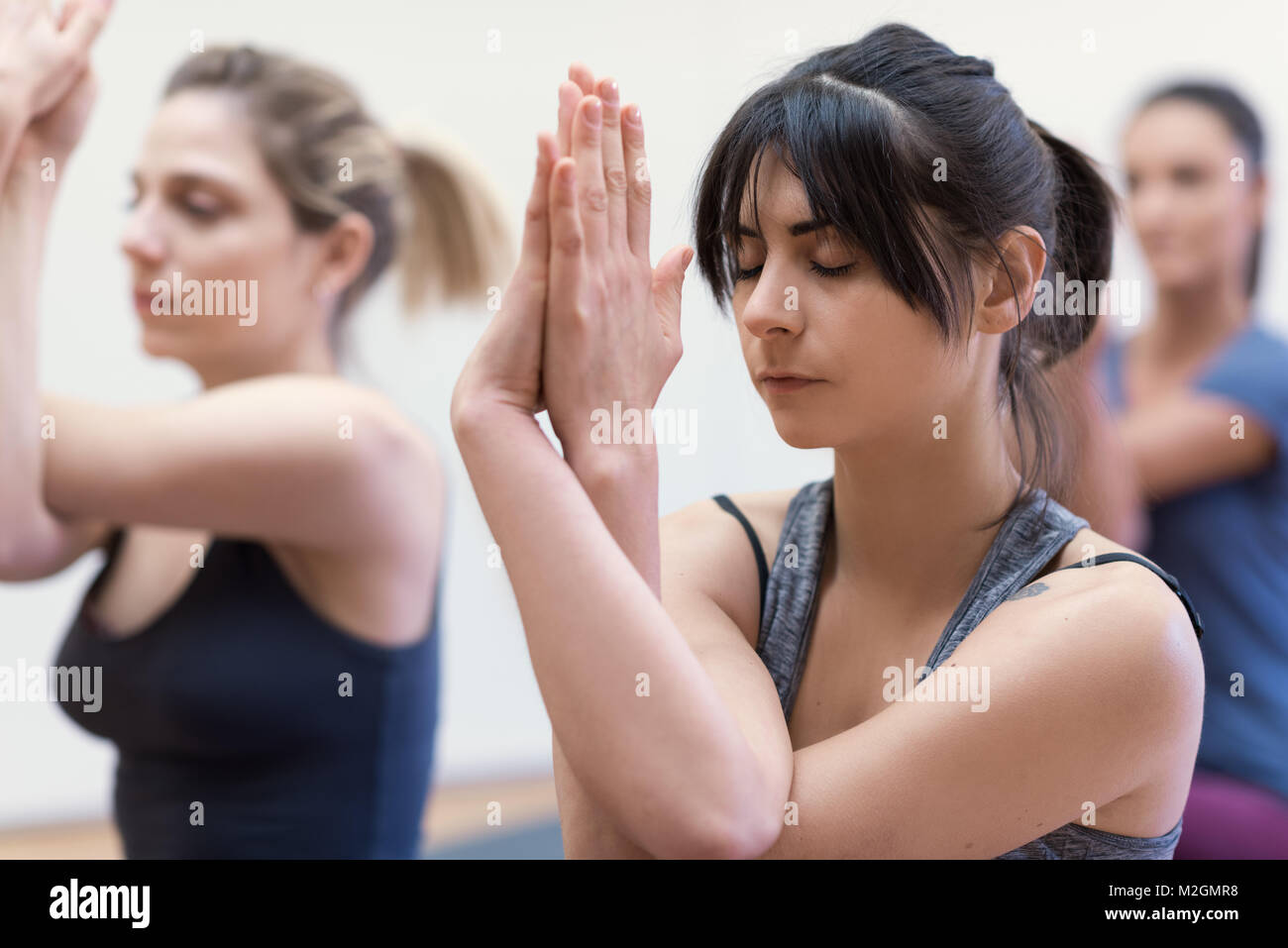 Women practicing yoga together, they are sitting and crossing their ...