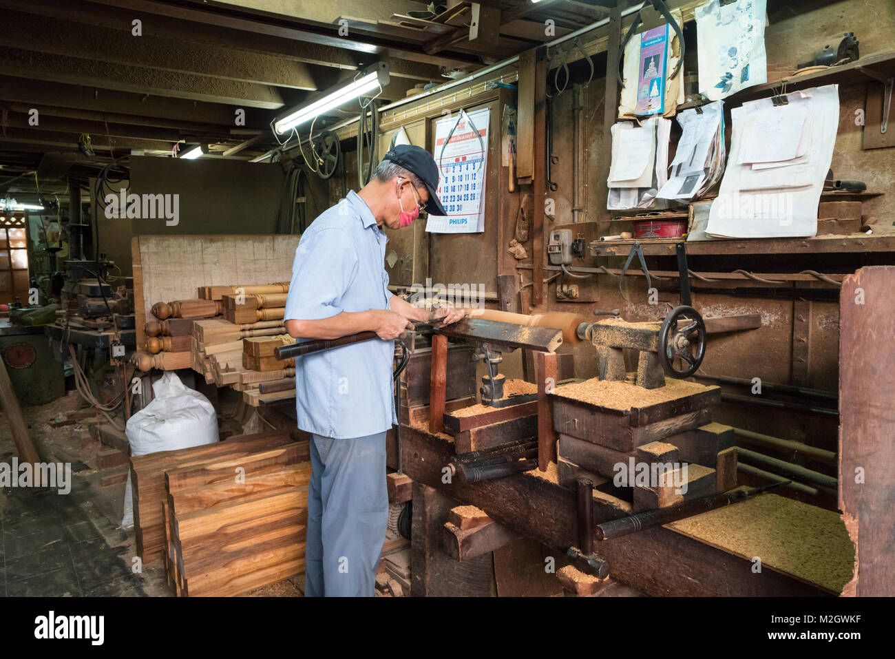A man working wood on a lathe in a laboratory in Bangkok, Thailand ...