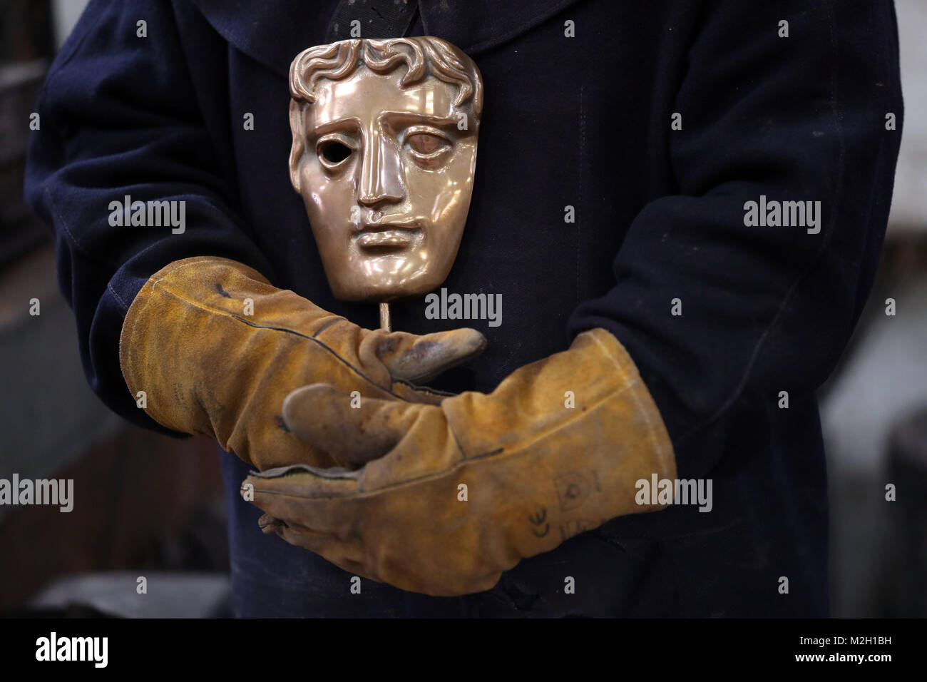 Furnaceman Billy Smith holds a finished BAFTA mask as finishing touches ...